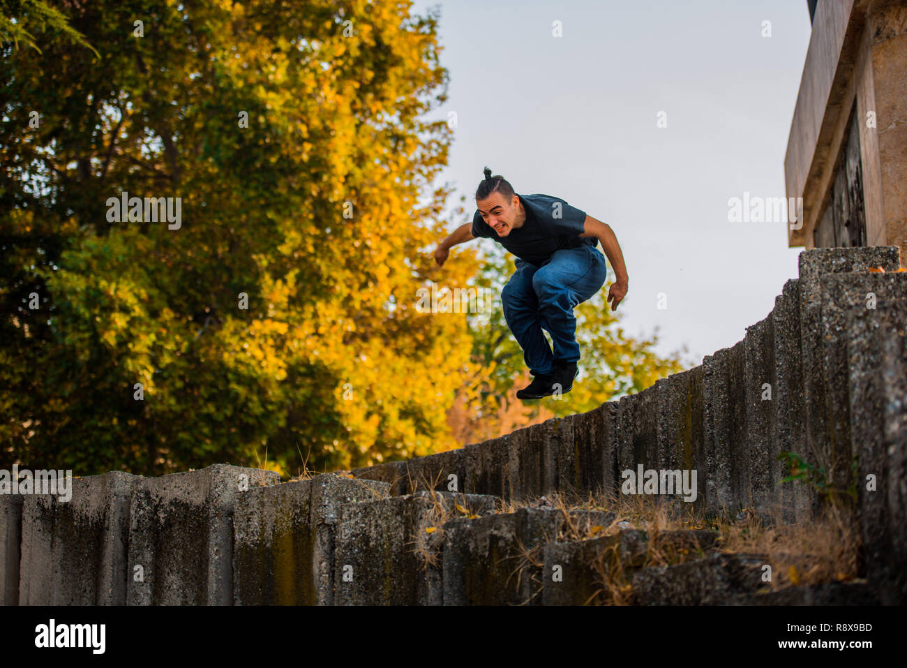Strong man while training parkour jumping over wall in park Stock Photo ...