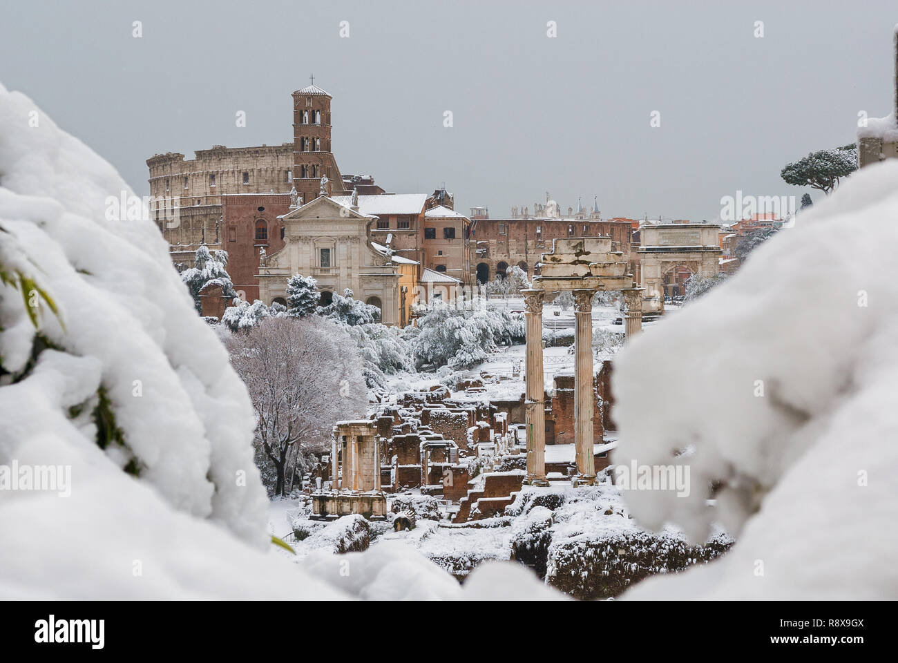 View of frozen Roman Forum ancient ruins and Coliseum through two snow ...