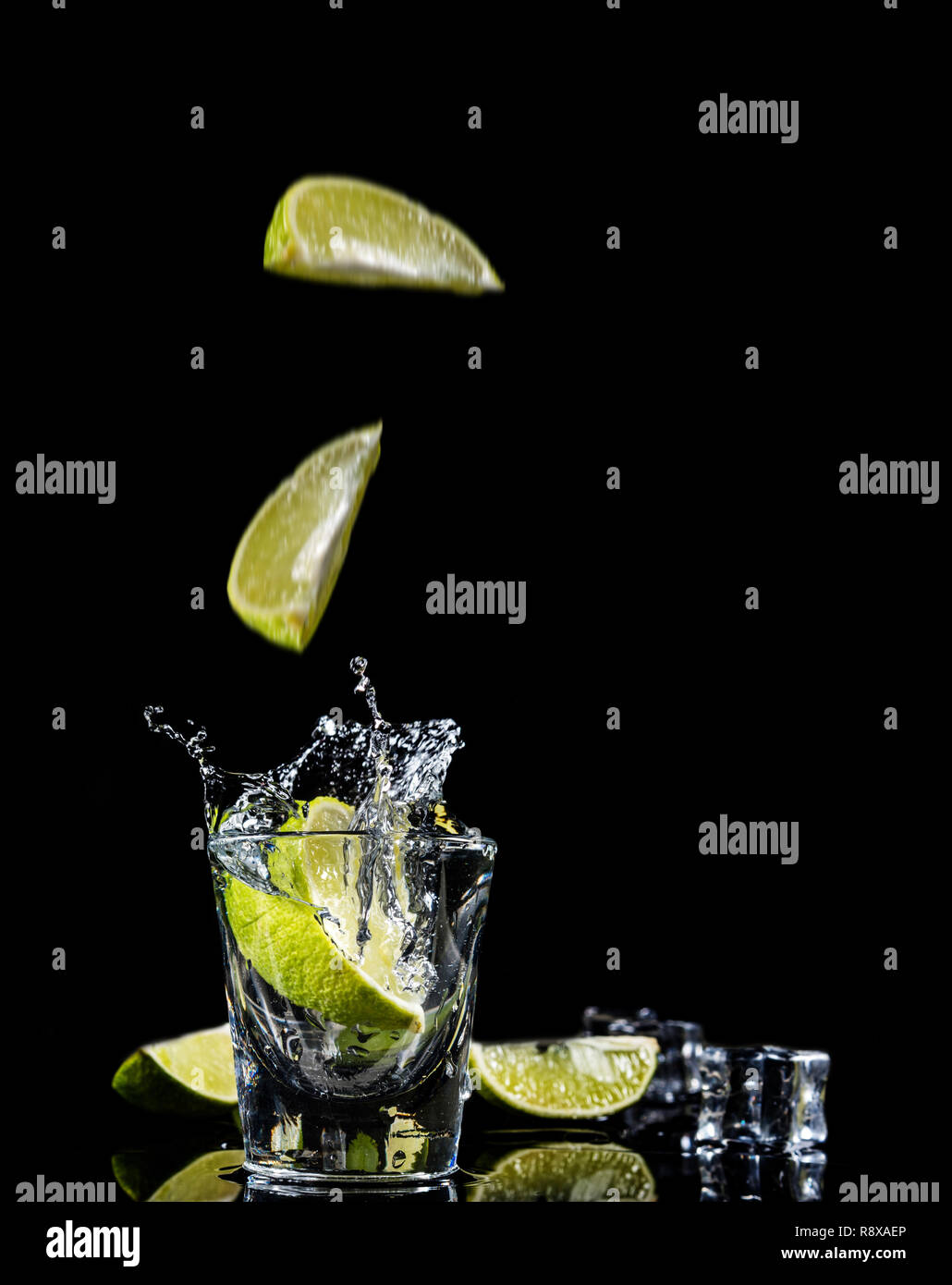 Mexican traditional Tequila splash lime on black background with ice ...