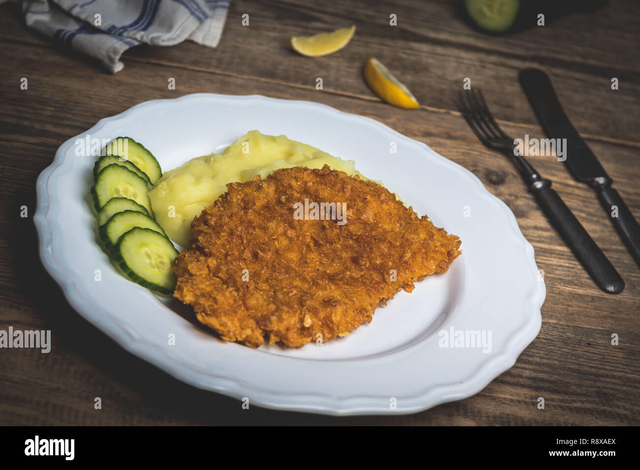 Chicken fried schnitzel with mashed potatoes and lemon on wood table ...