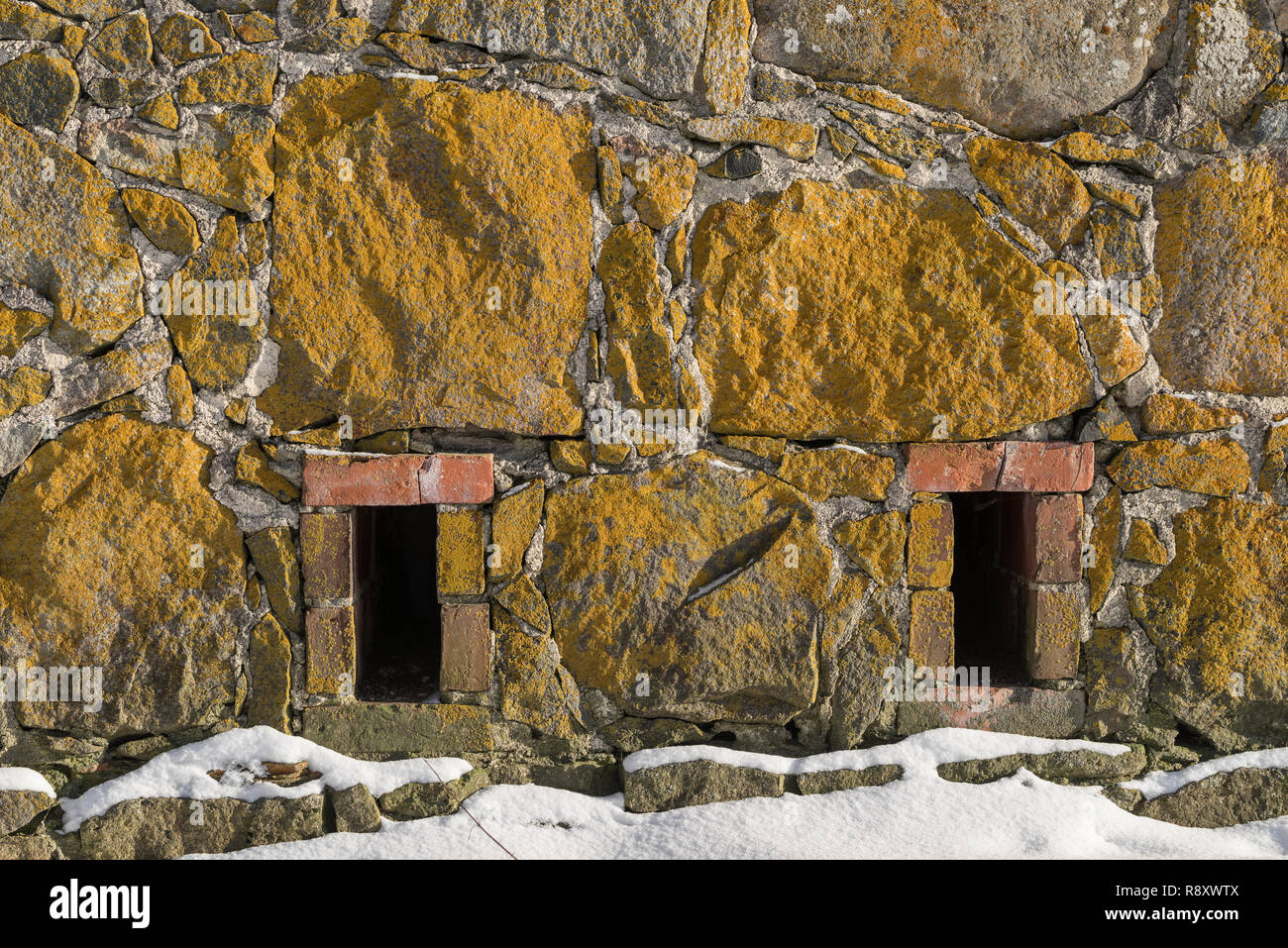 Stone wall texture and windows with red frames, natural background ...
