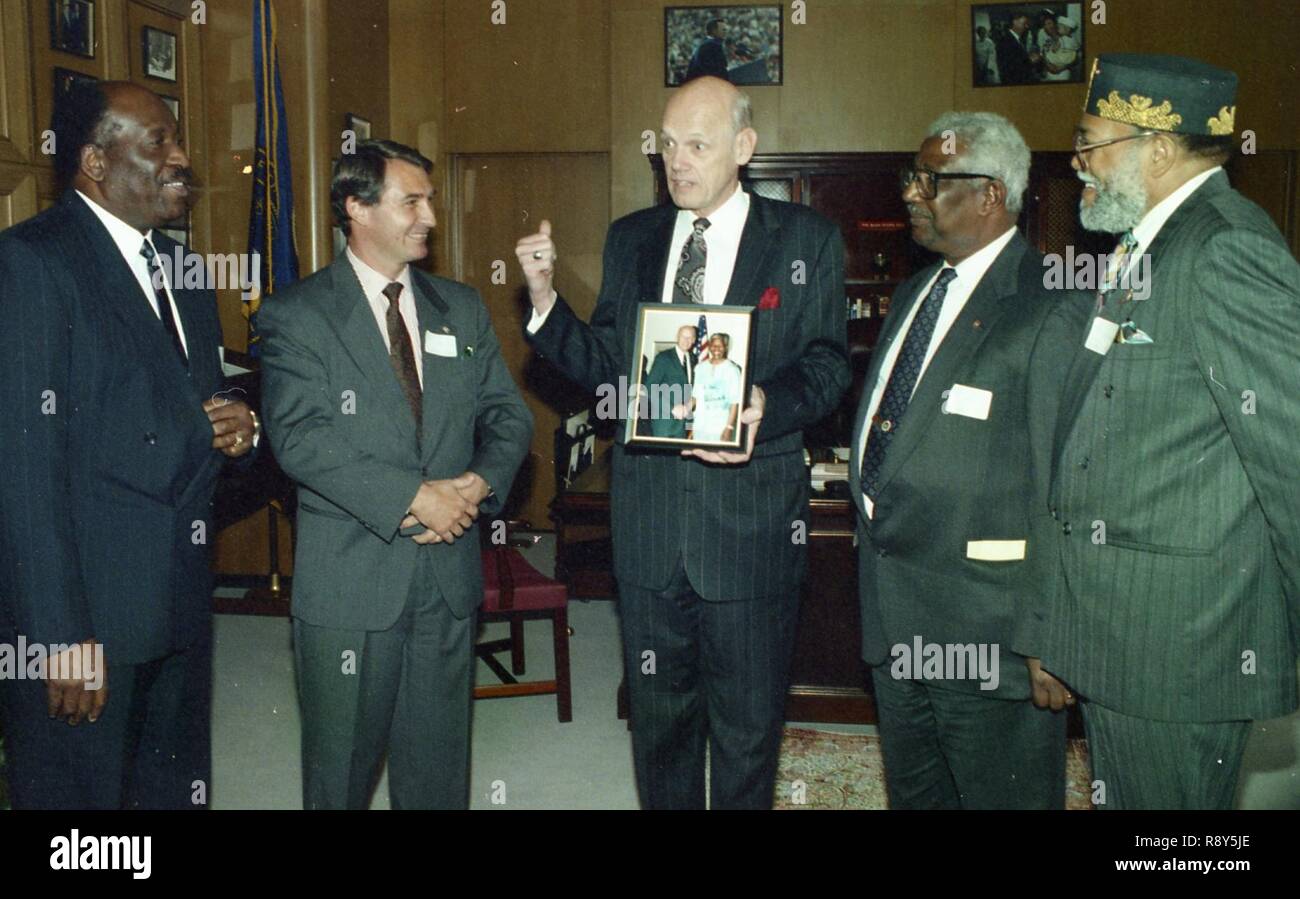 FIVE MEN ARE STANDING IN THE OFFICE HAVING A CONVERSATION WITH ONE MAN ...