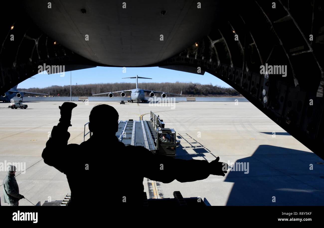 A loadmaster assigned to the 137th Airlift Squadron uses hand gestures ...