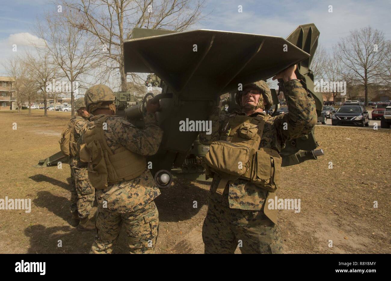 Marines lift the left rear trail of a M777 howitzer during a gunner and ...