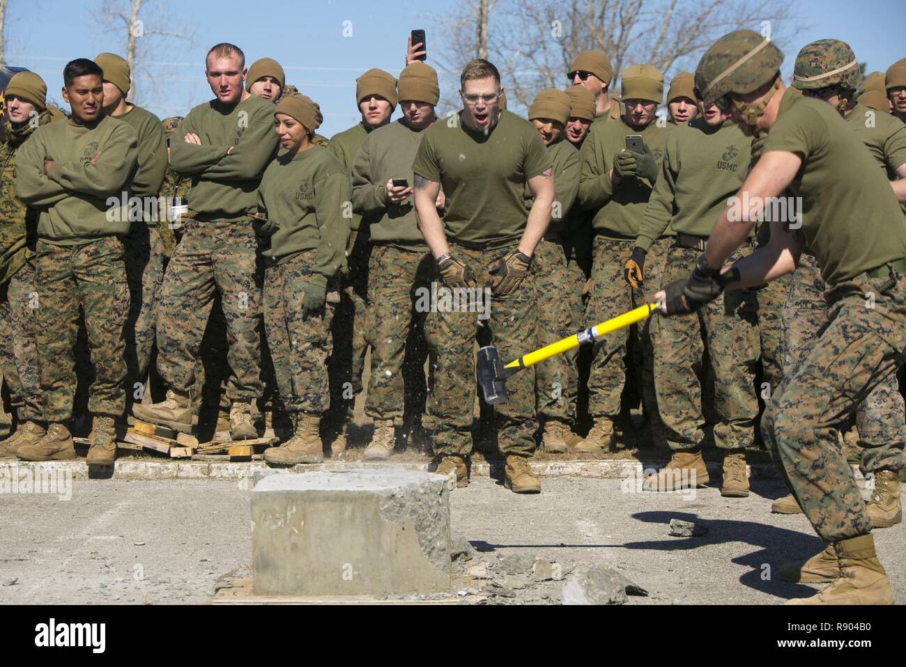 A Marine uses a sledgehammer to break a slab of concrete during the ...