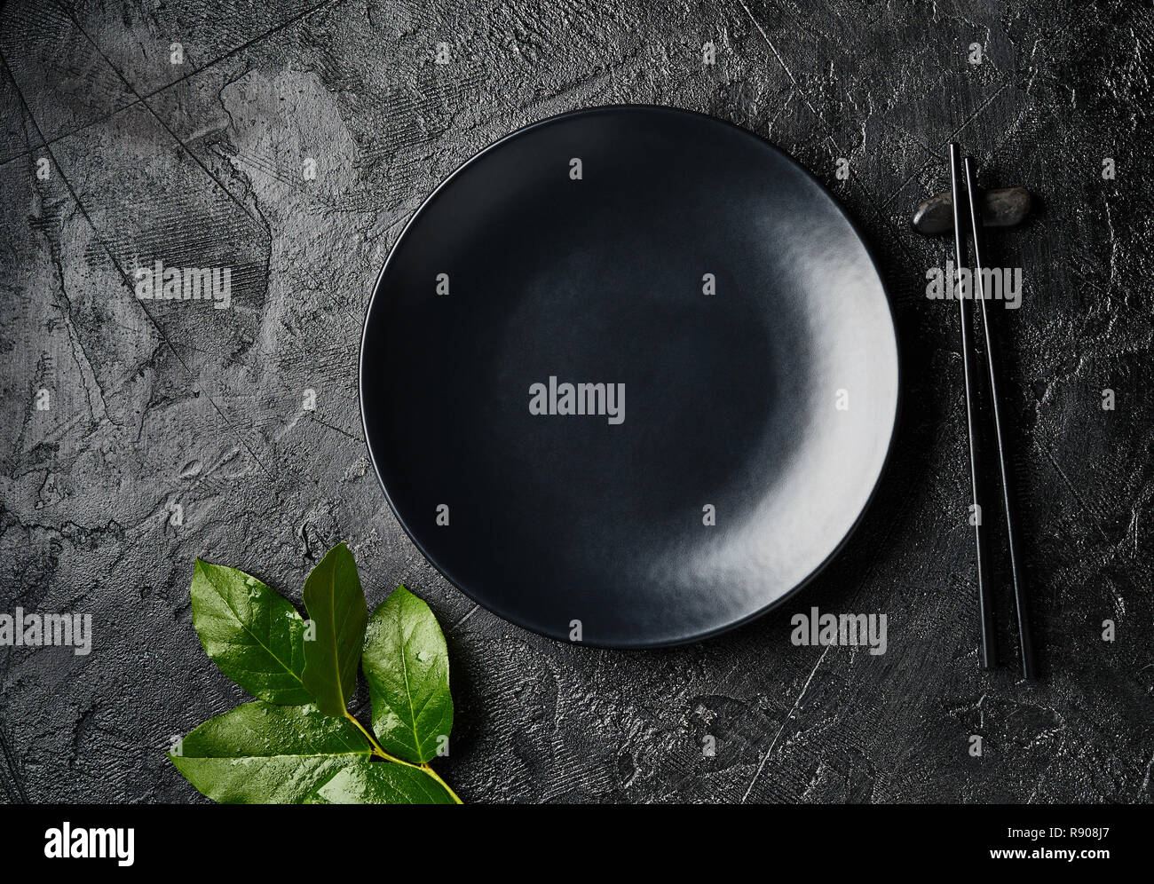 Dark empty plate of asian food with black chopsticks on black slate ...