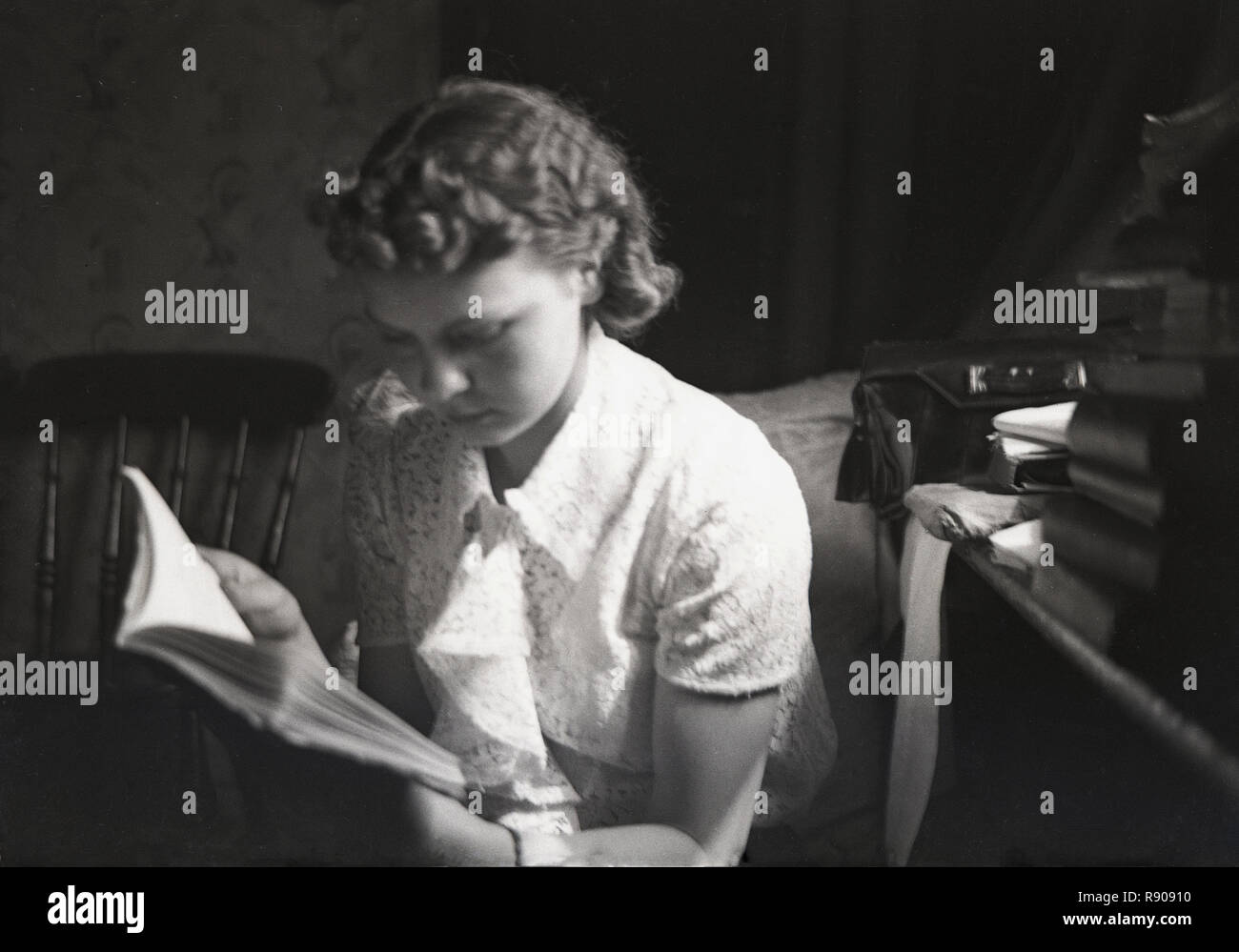 1940s, historical, a young lady inside a room sitting reading a book ...