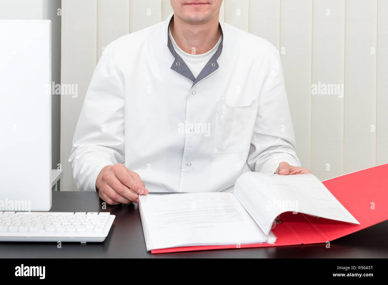 Doctor working with computer and writing on paperwork. Modern hospital ...