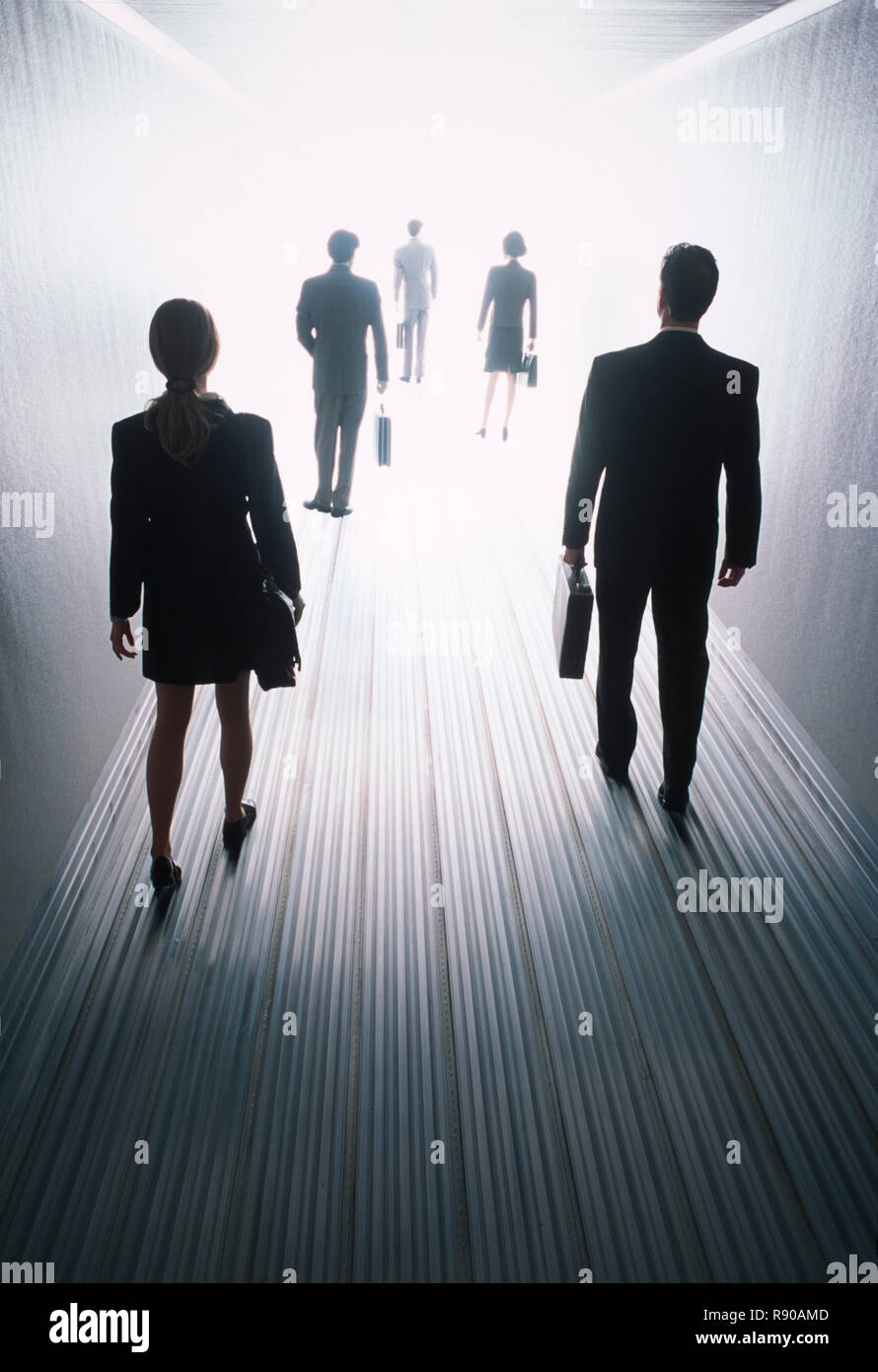 A line of people, men and women in silhouette, walking towards a very ...