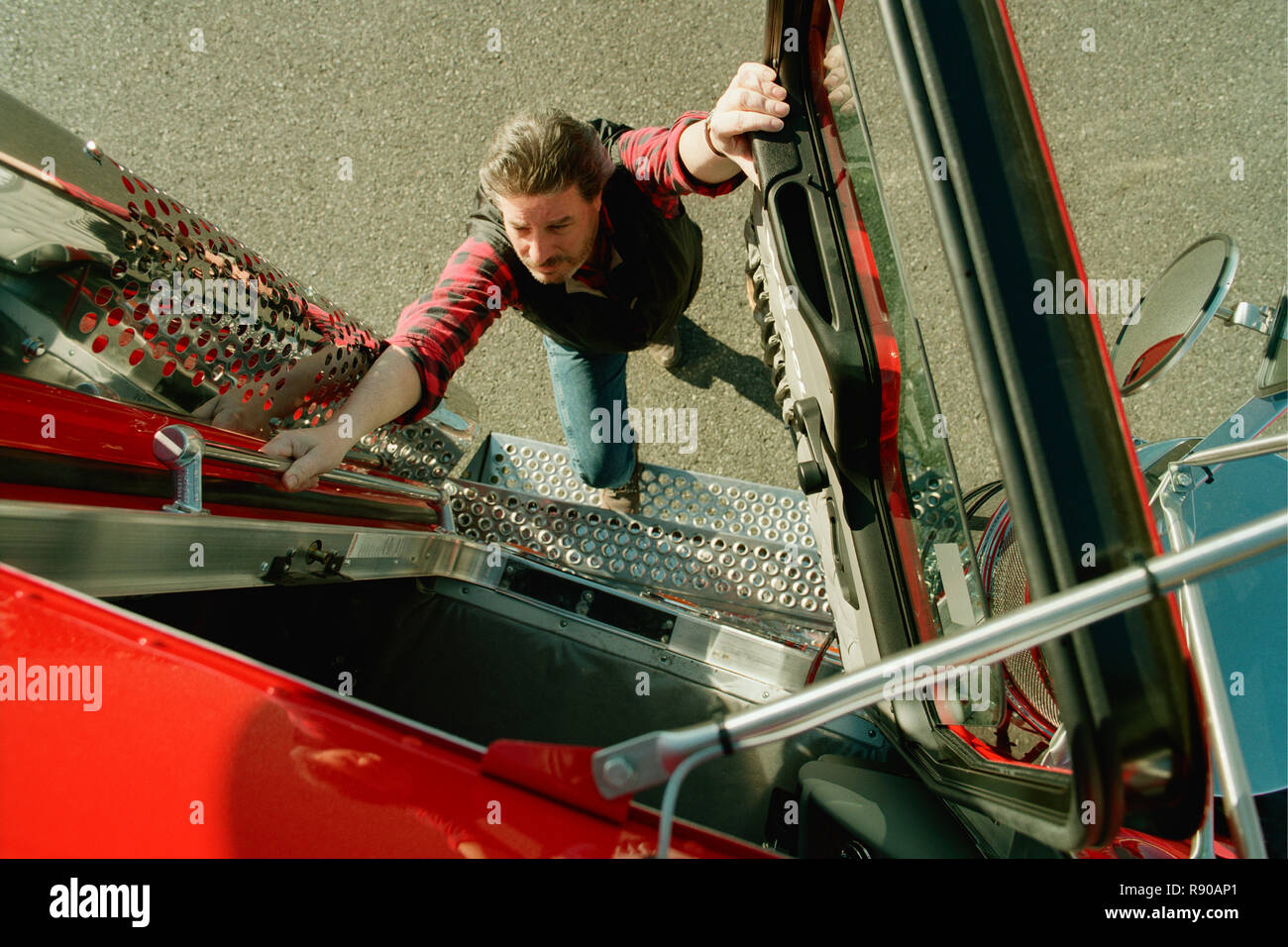 A view looking down of a truck driver climbing into the cab of Kenworth ...