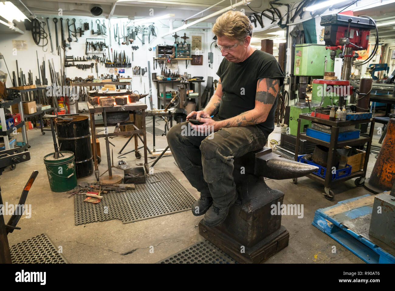 Male Blacksmith checking his phone for messages while sitting on an ...