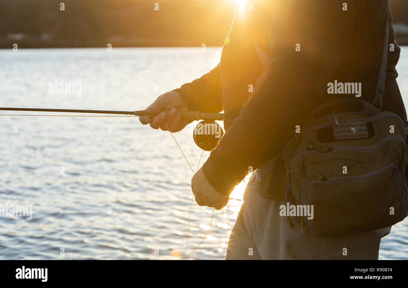 A closeup view of a the hands of a fly fisherman retrieving his line ...