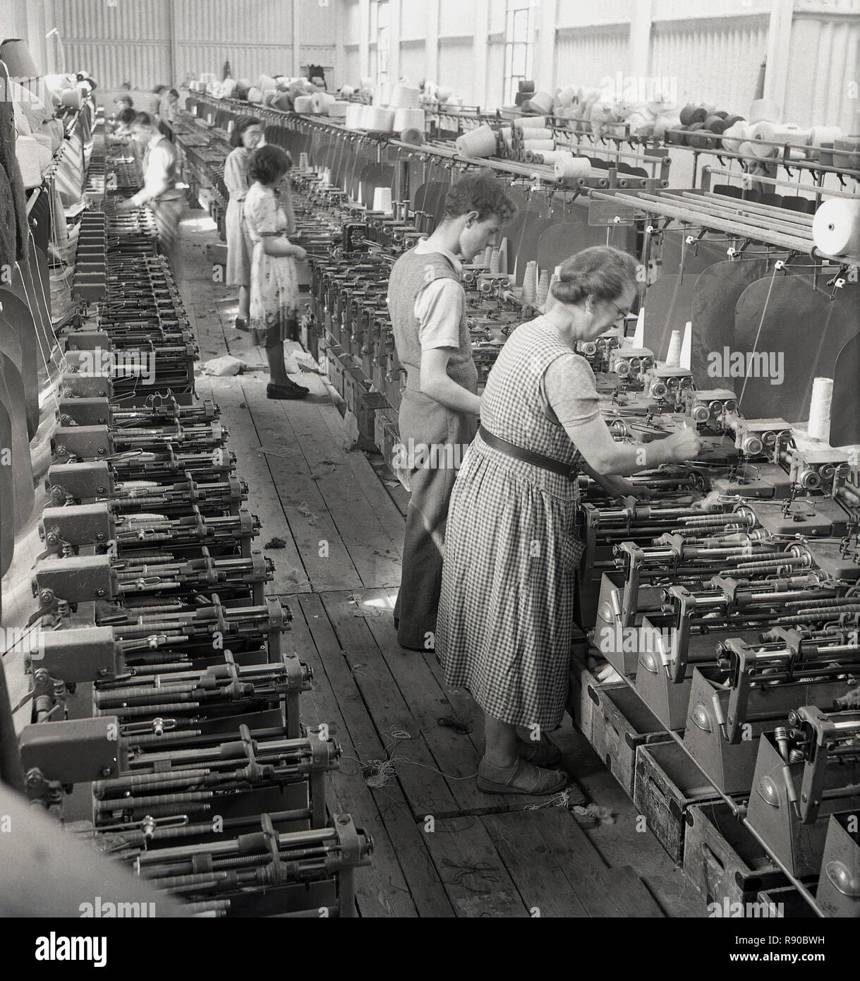 1950s, historical, workers on a factory floor standing using mechanical ...