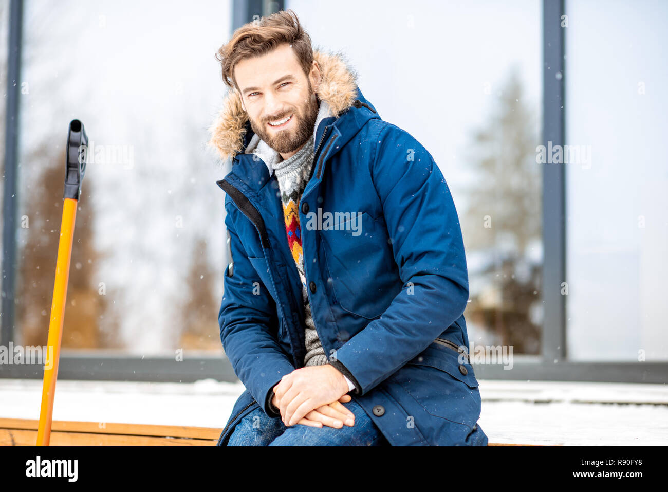 Portrait of a handsome man in winter clothes sitting on the terrace of ...