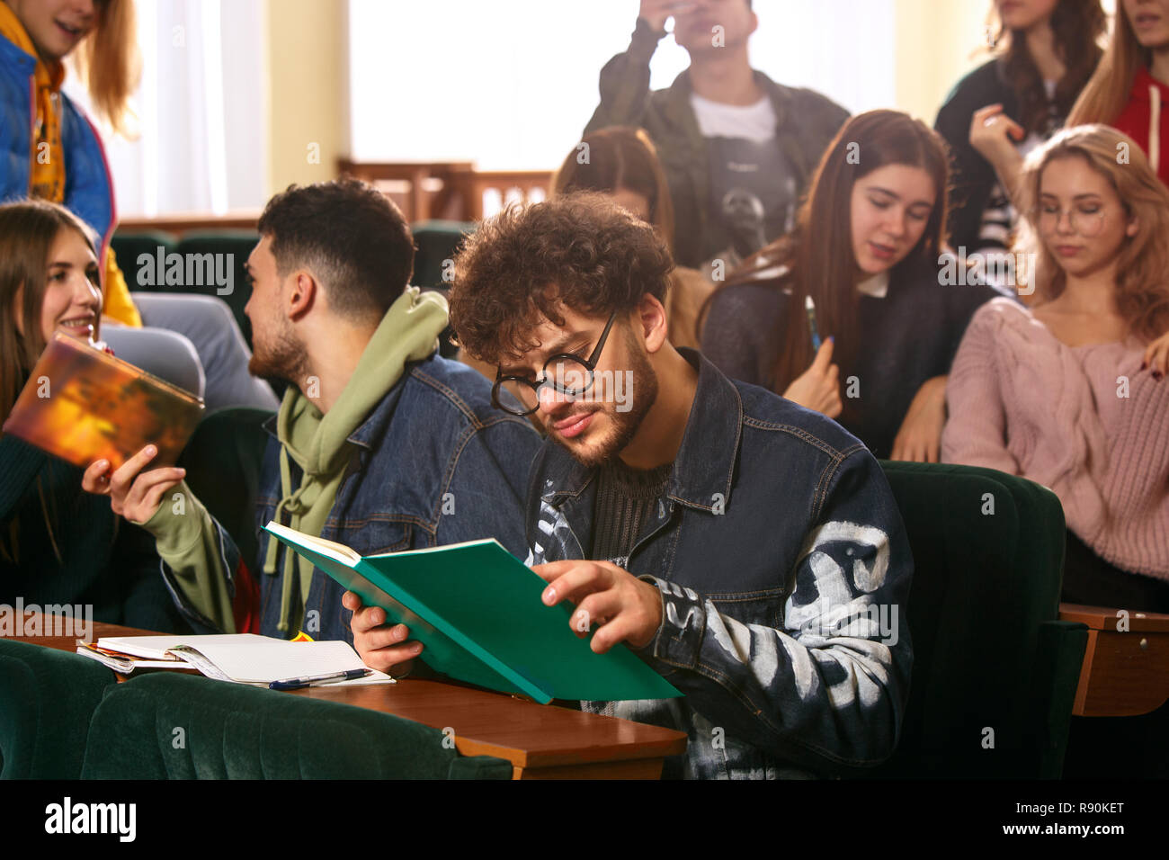 The group of cheerful students sitting in a lecture hall before lesson ...