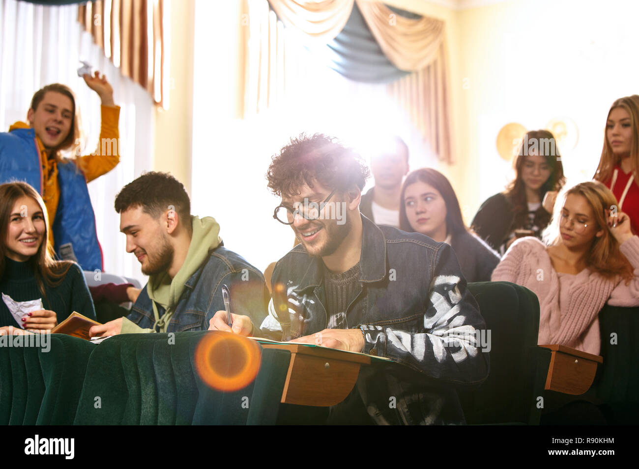 The group of cheerful students sitting in a lecture hall before lesson ...