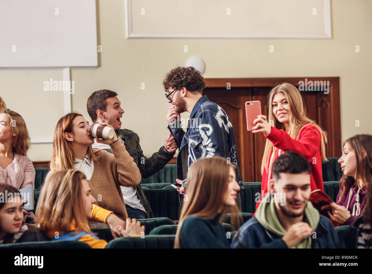 The group of cheerful students sitting in a lecture hall before lesson ...