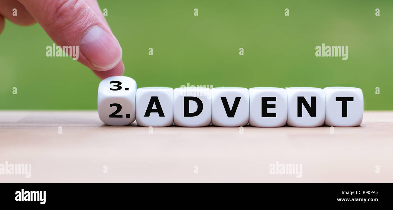 Hand is turning a dice and changes the word "2.Advent" to "3.Advent" as ...