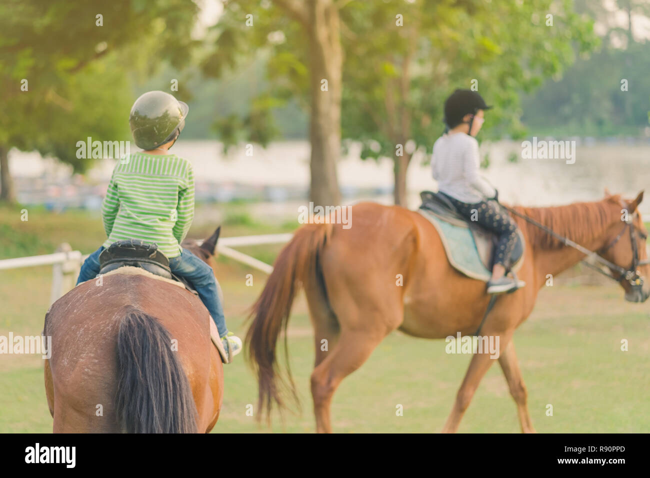 Kids learn to ride a horse near the river before sunset Stock Photo - Alamy