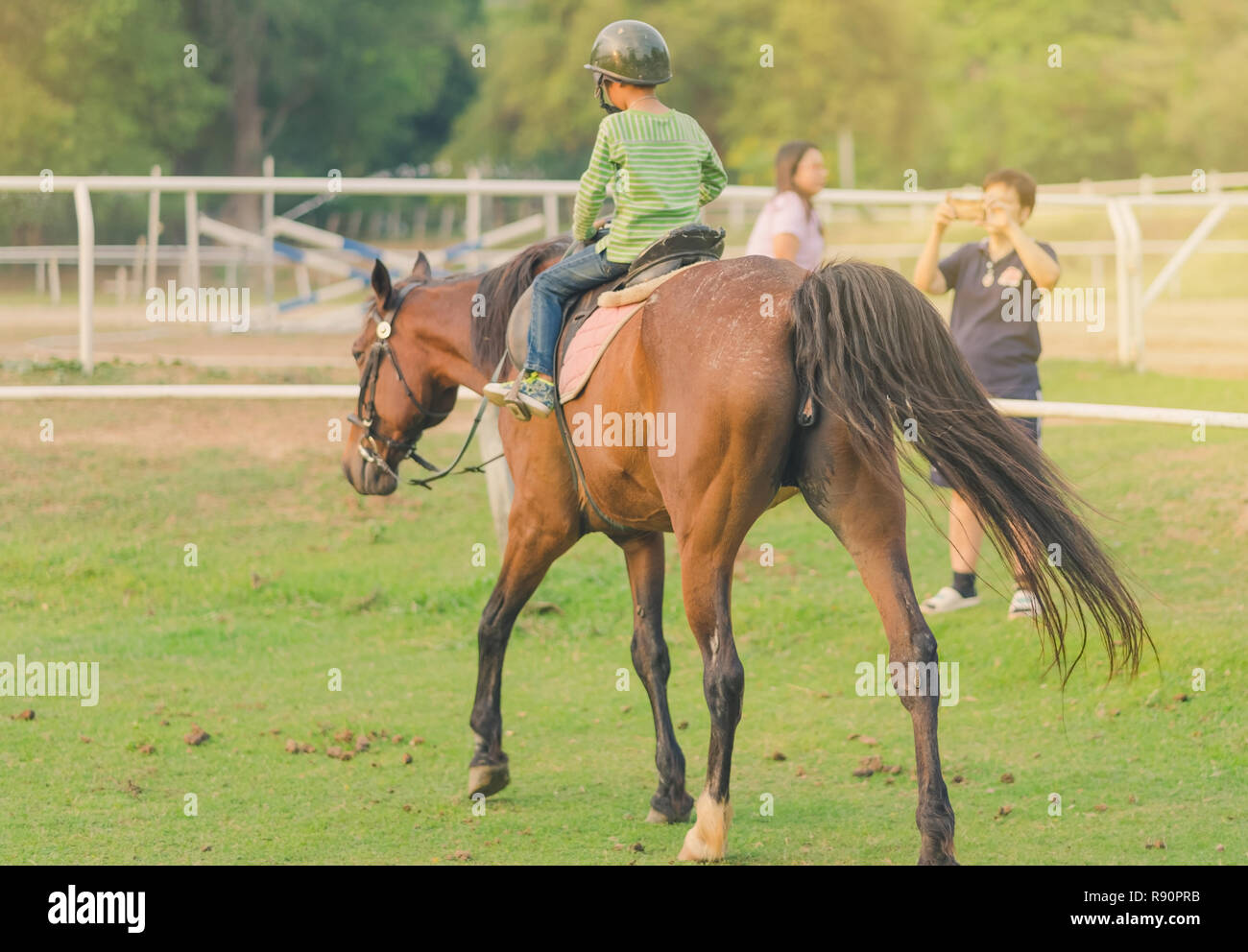 Kids learn to ride a horse near the river before sunset Stock Photo - Alamy