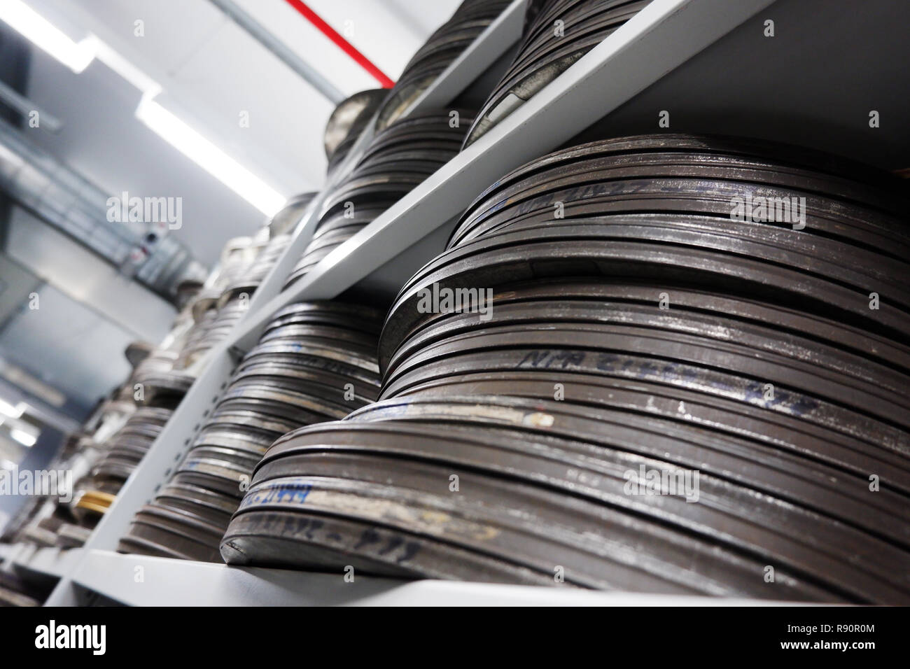 old reels of film in silver cans stacked on a shelf in a cold storage ...