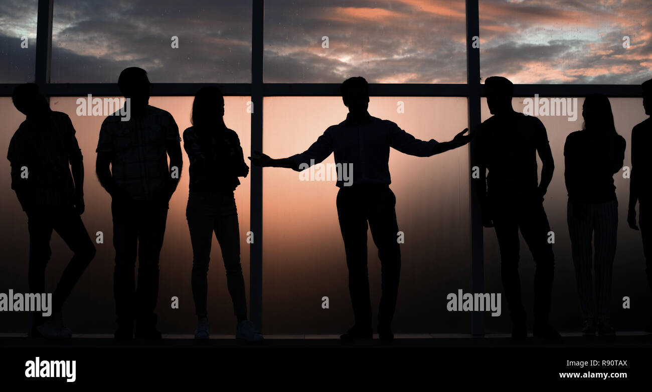 leader and a group of young people standing near a large window Stock ...