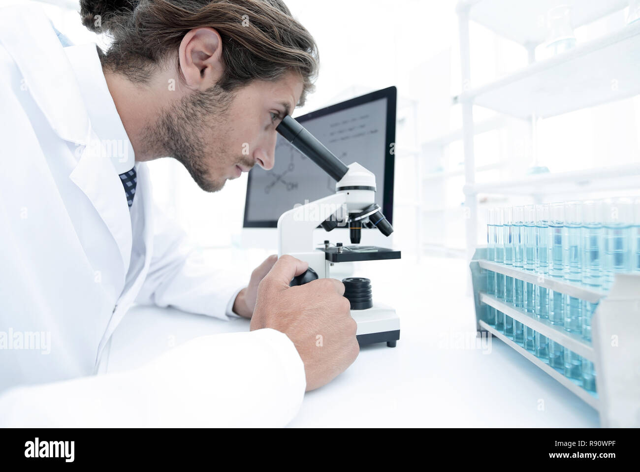 Young laboratory scientist looking at microscope in laboratory Stock Photo - Alamy