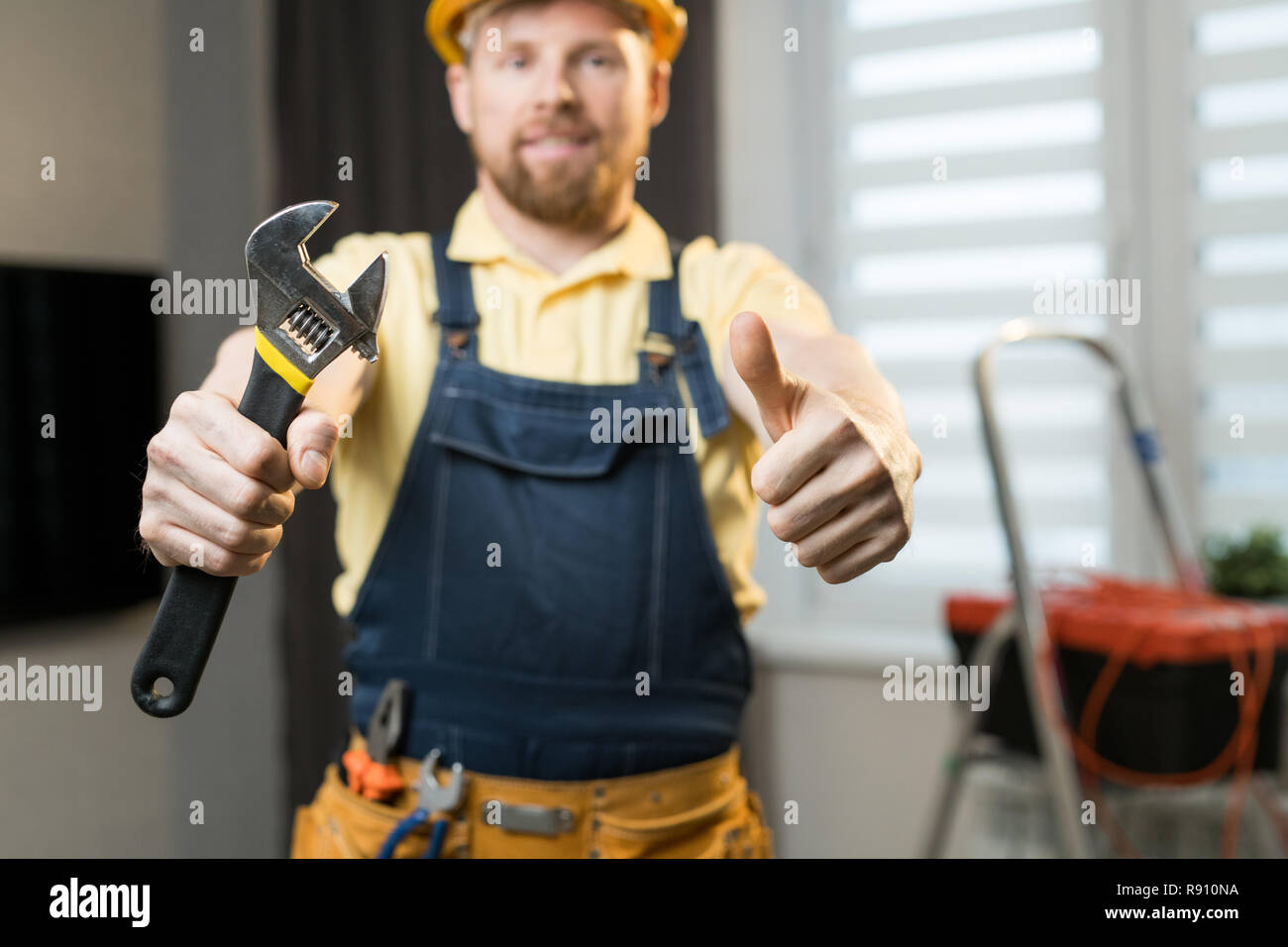 Positive handyman showing work tool Stock Photo - Alamy