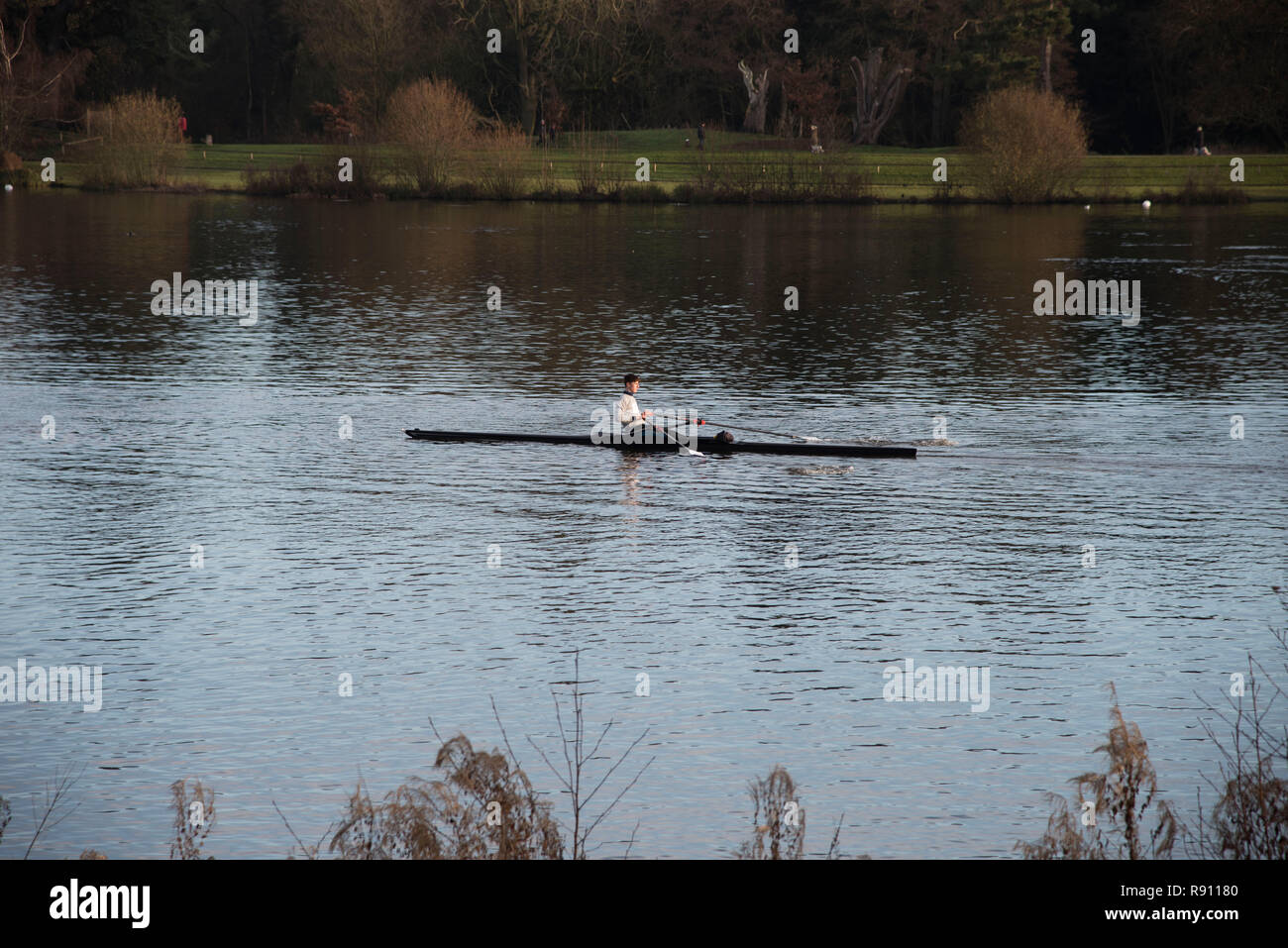 A single person enjoying being out on the lake rowing in his scull boat ...
