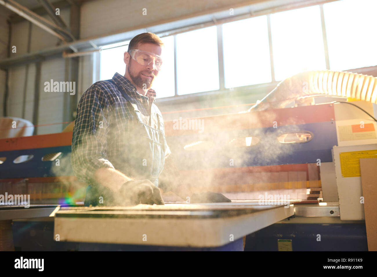 Bearded employee working in dusty workshop Stock Photo - Alamy