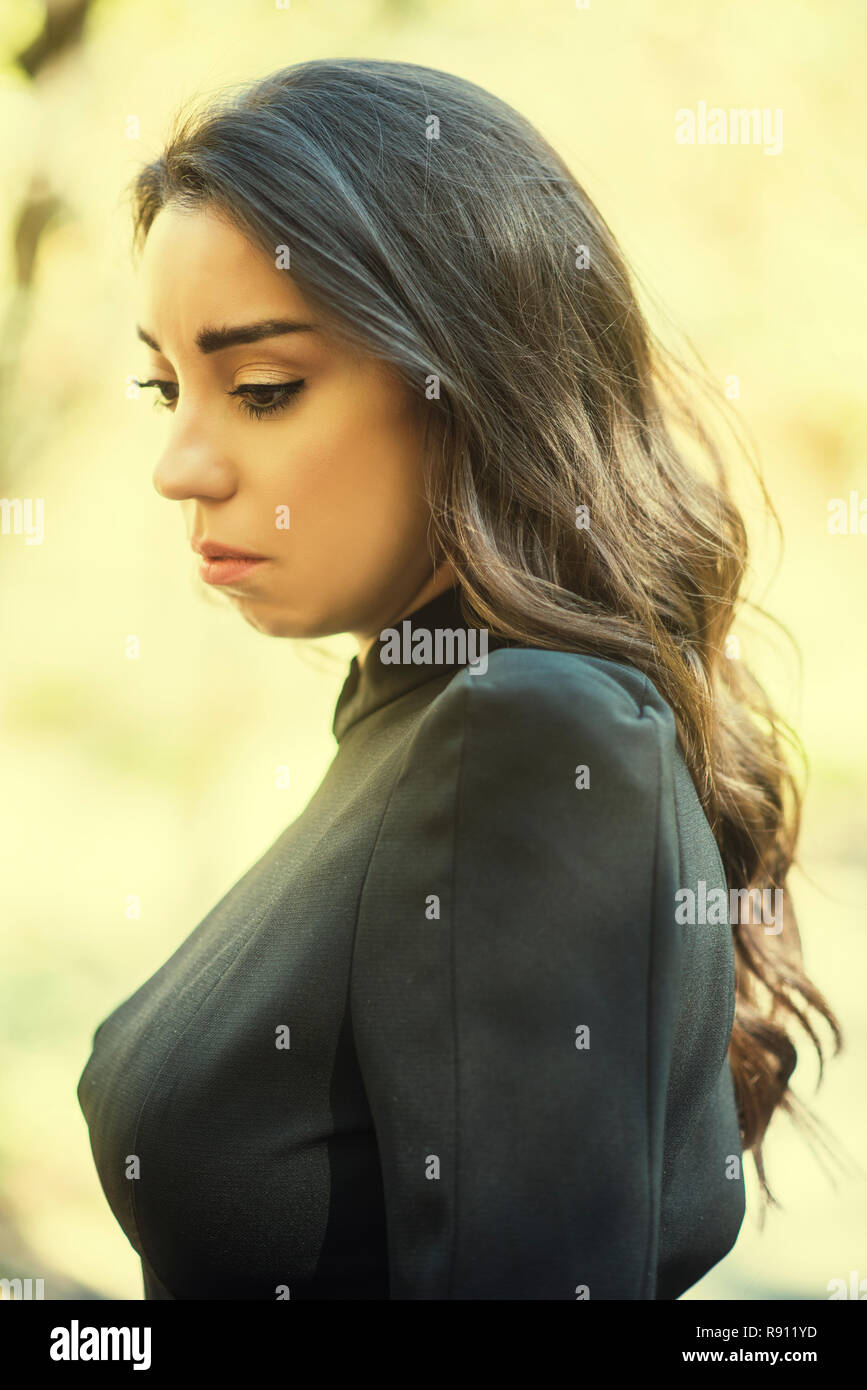 Side view of a sad young woman standing outdoors Stock Photo - Alamy