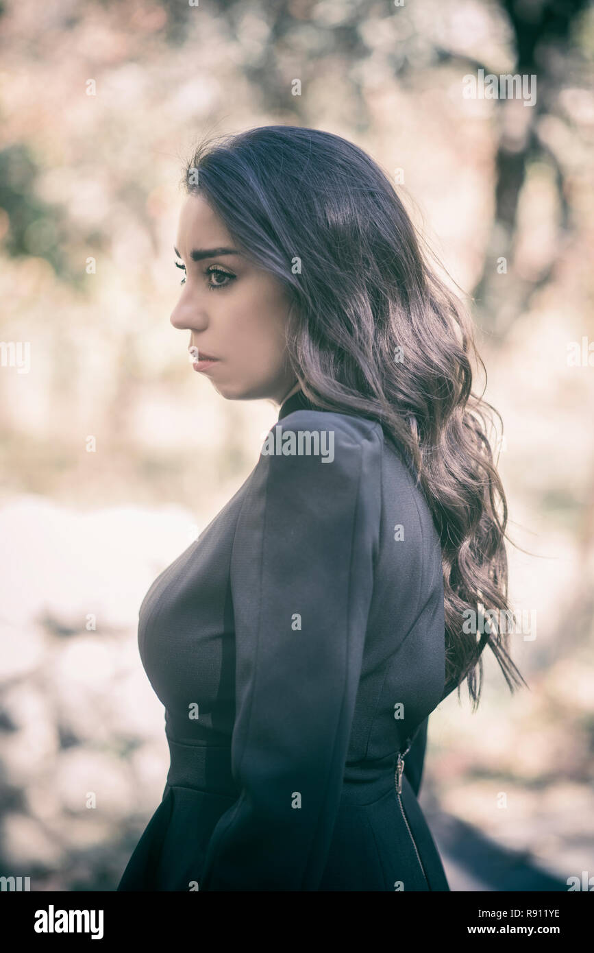 Side view of a sad young woman standing outdoors Stock Photo - Alamy