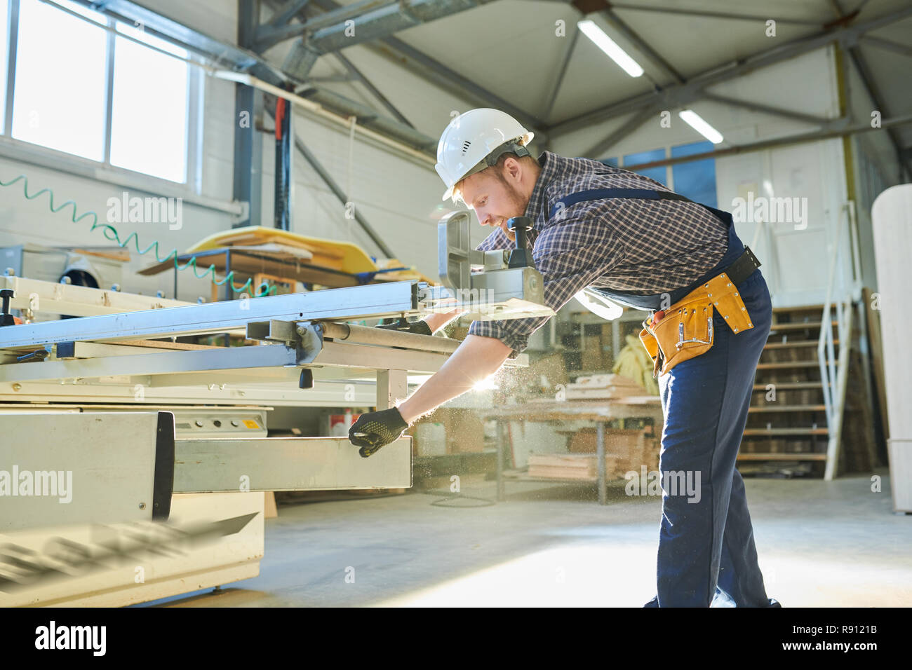 Young worker adjusting assembling machine at furniture plant Stock ...