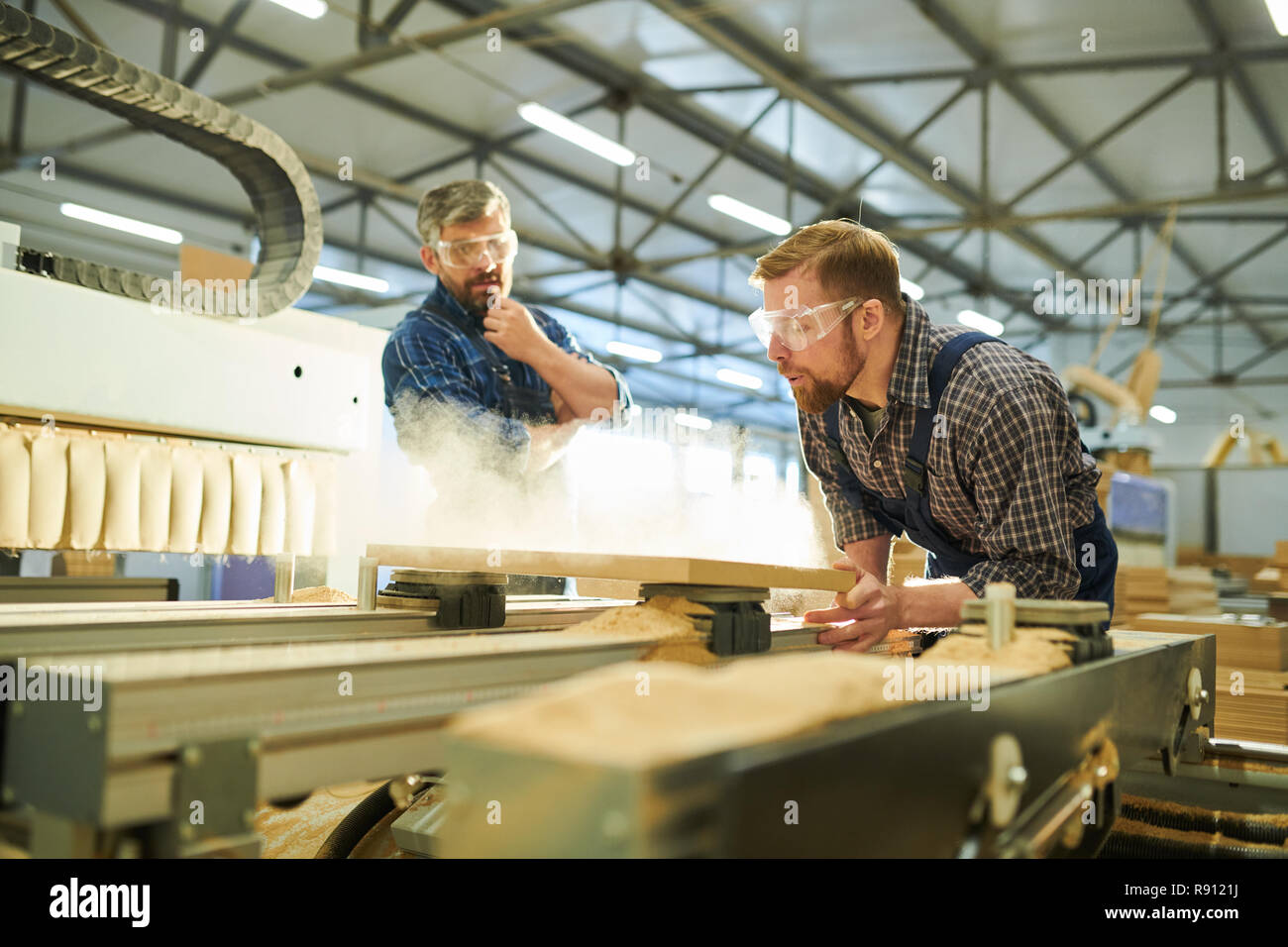Worker blowing off dust from wooden detail Stock Photo - Alamy
