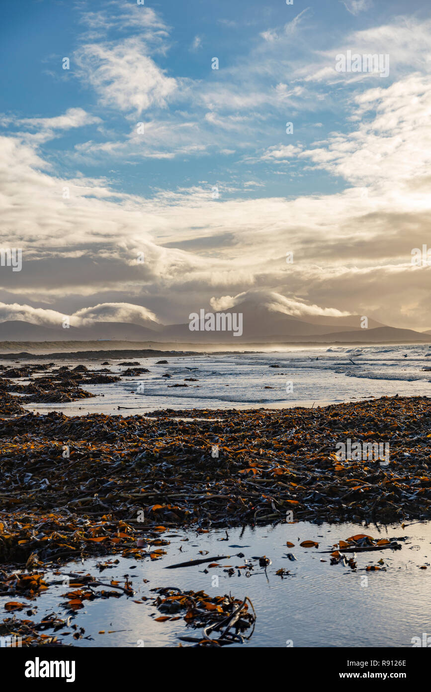 The hills of South Uist amongst dramatic skies with rocks and seaweed ...