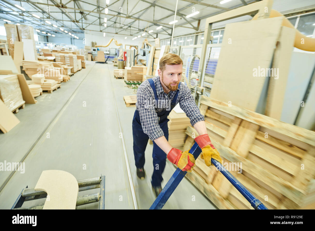 Handsome young worker pushing pallet jack over factory warehouse Stock ...