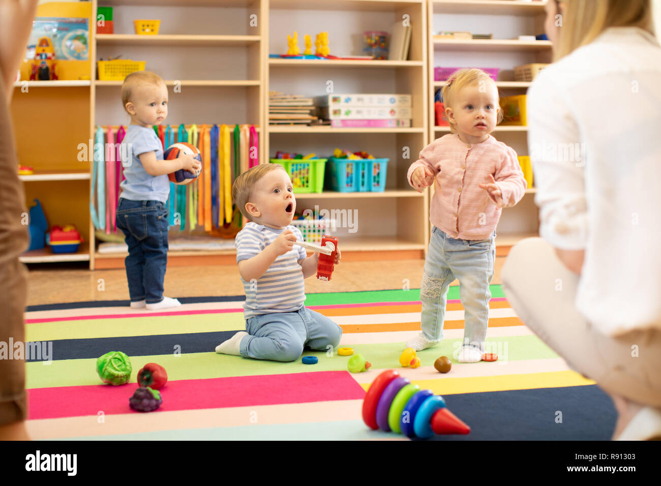 babies children playing in kindergarten with a teacher Stock Photo - Alamy