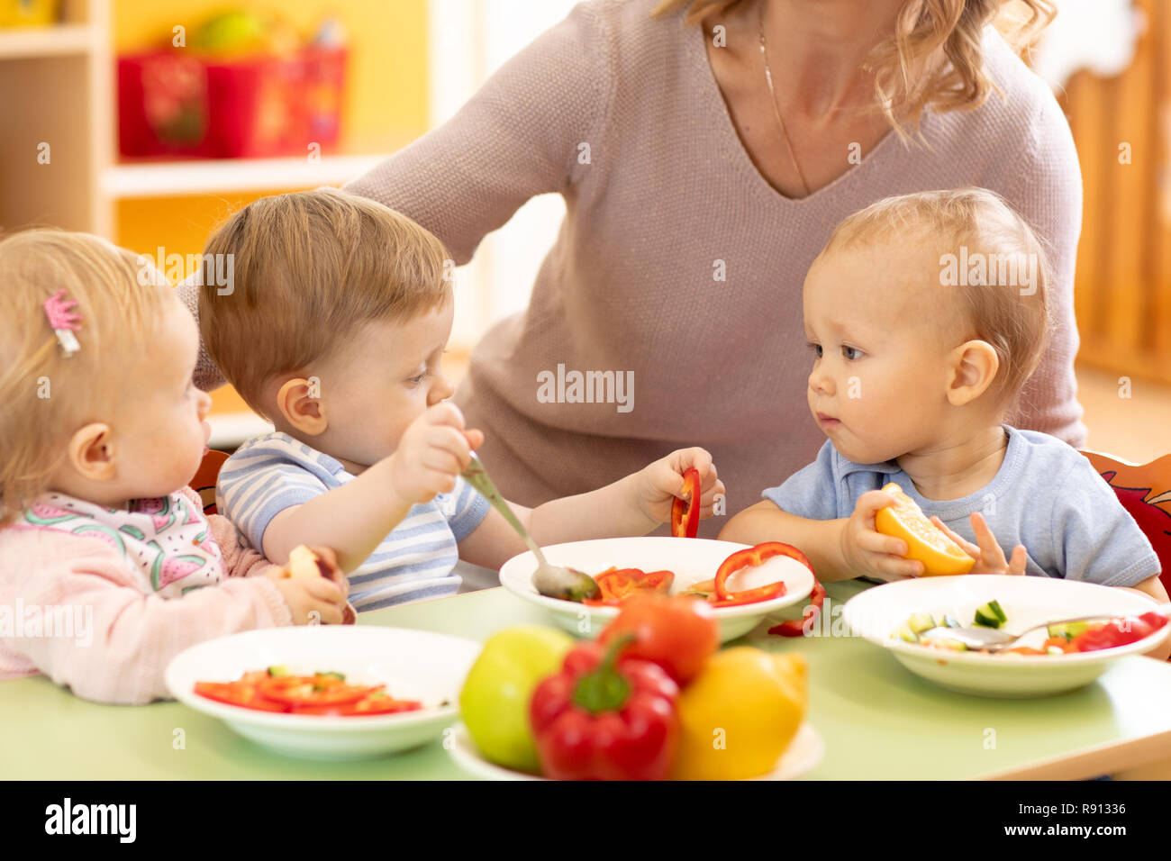 Babies eating healthy lunch in nursery or daycare centre Stock Photo ...