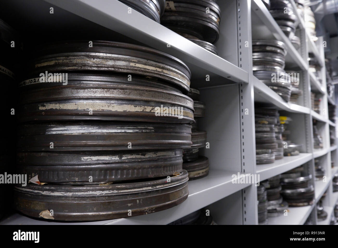 old reels of film in silver cans stacked on a shelf in a cold storage ...