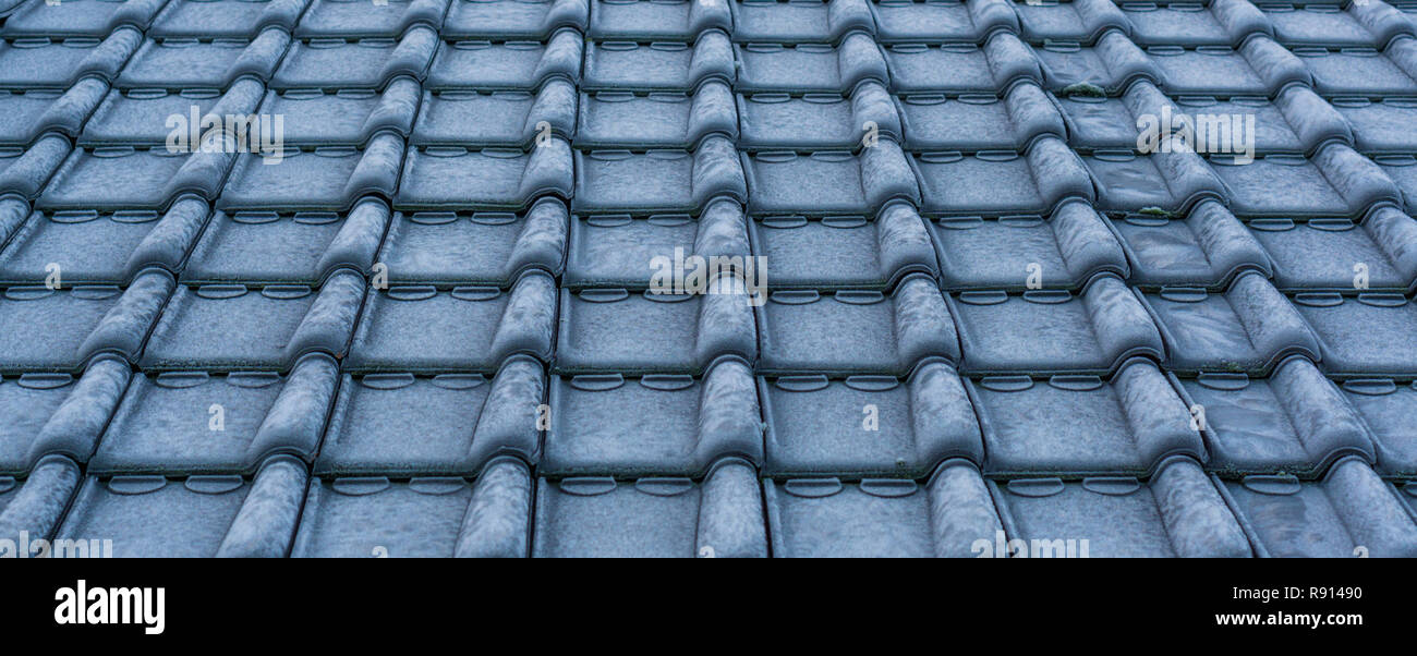 pattern of frozen rooftop tiling in macro closeup, cold winter season ...
