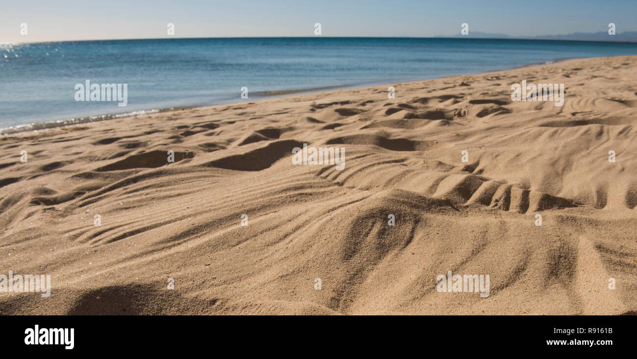 Closeup view across an empty sandy tropical beach to the open ocean ...