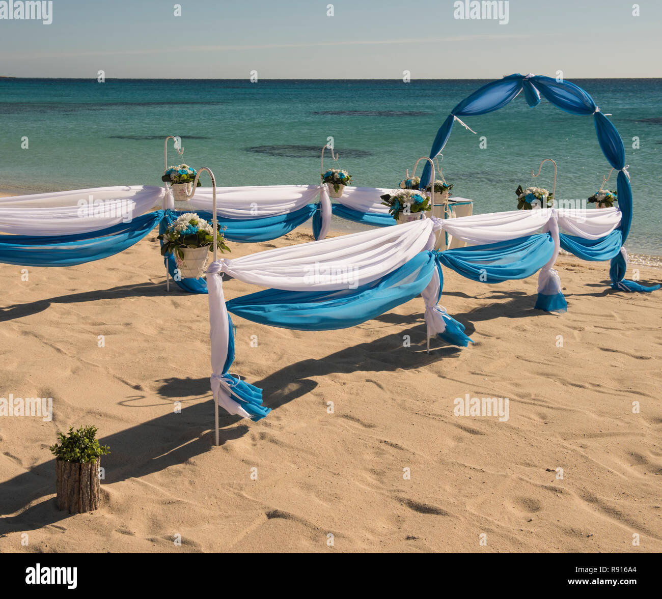Setup of wedding day marriage aisle with drapes and arch on sandy ...