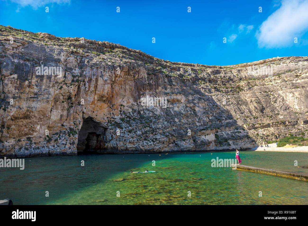 Young lady in front of a huge cliff with a green water beach in Malta ...