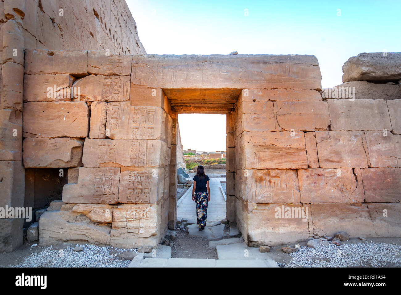 A young woman walking through a big stone door in a egyptian temple ...