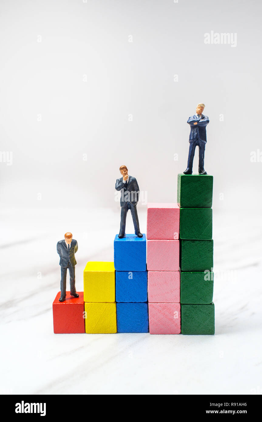 Miniature businessmen stand on wooden blocks symbolizing steps to ...