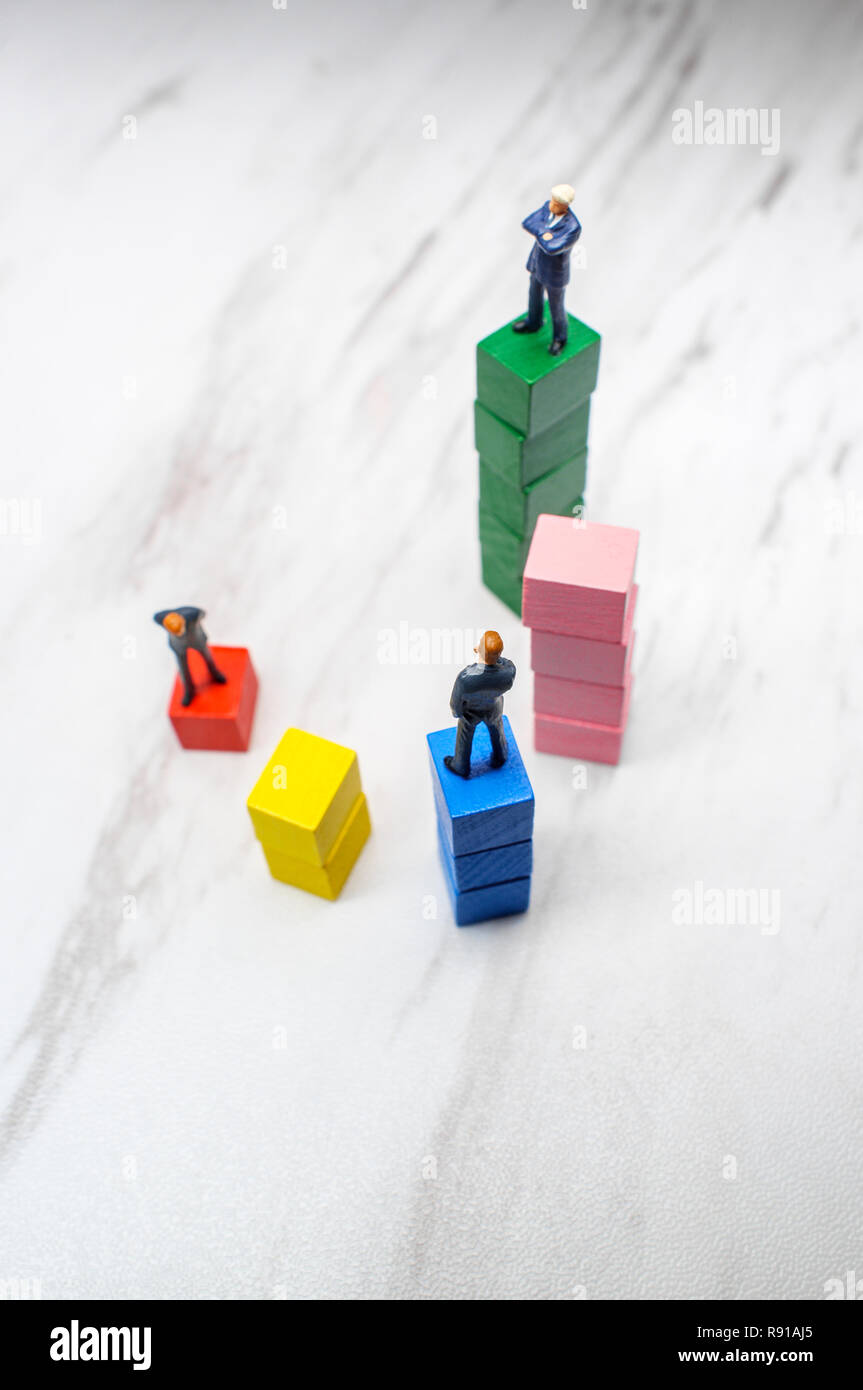 Miniature businessmen stand on wooden blocks symbolizing steps to ...