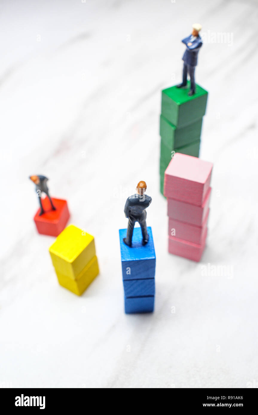 Miniature businessmen stand on wooden blocks symbolizing steps to ...