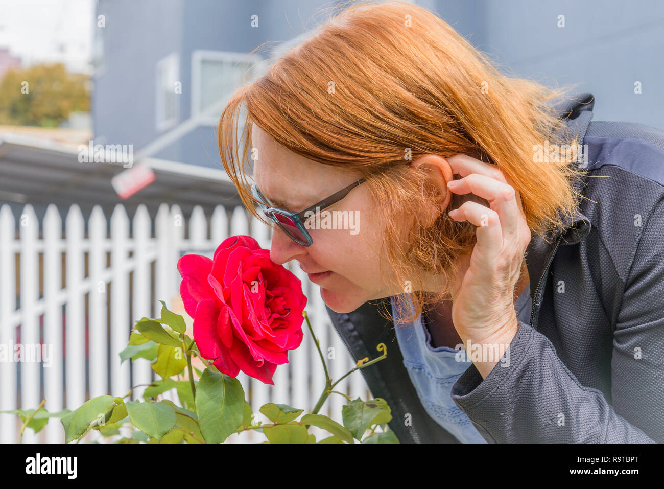 Redhead woman smelling rose Stock Photo - Alamy
