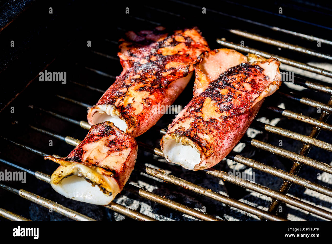 Grilling squid or cuttlefish on a coal barbecue grill. Traditional ...