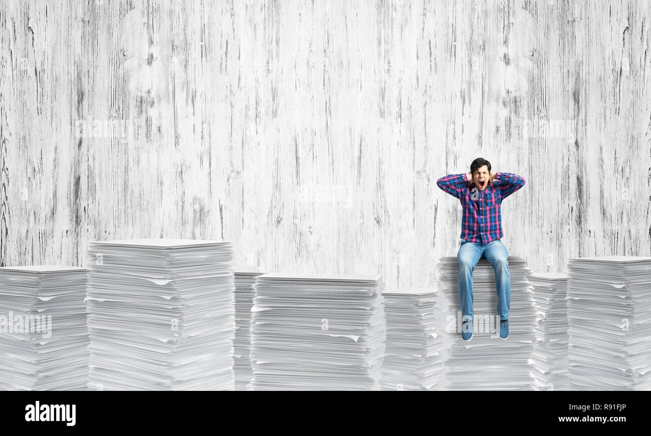 Attractive man sitting on pile of paper documents Stock Photo - Alamy